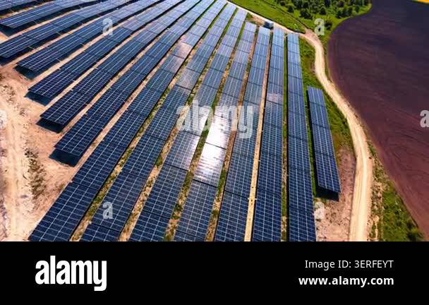 Solar panels between farmland and plowed soil. Angled photovoltaic ...