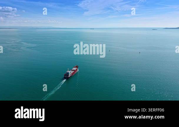 Freighter crossing calm turquoise bay. Scattered vessels on horizon ...
