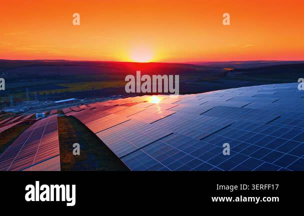 Golden hour light reflecting off solar farm panels at dusk. Warm orange ...