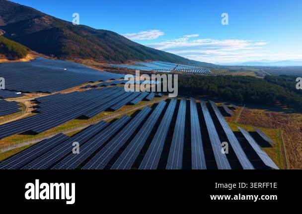 Solar arrays spanning mountain foothills. Rows extend from forested ...