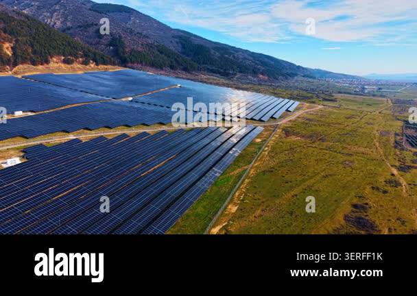 Large solar farm beside green pastures and mountain slope. Diagonal ...