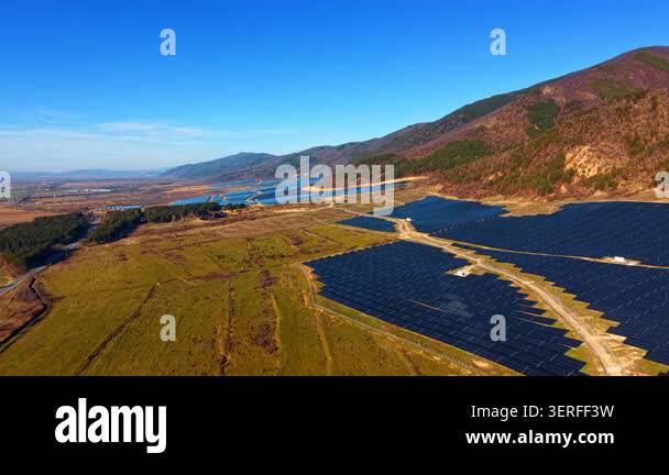 Wide panorama of solar arrays and pastureland in mountain foothills ...