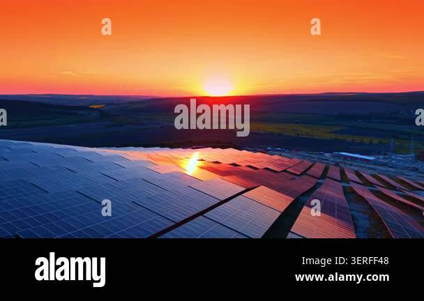 Solar farm at sunset with sun reflection. Orange gradient sky over dark ...