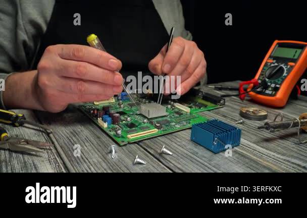 Technician focuses on repairing an electronic circuit board, using a ...