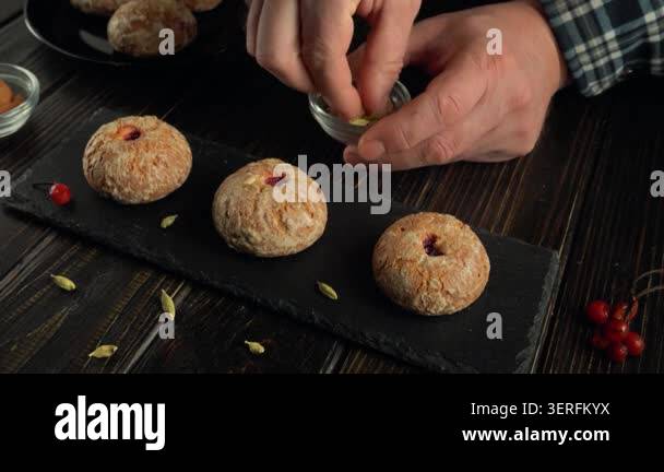 Hands of a man in a plaid shirt sprinkle cardamom seeds over three ...