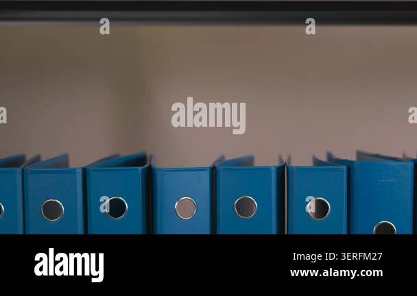 Close-up of blue ring binders lined up neatly on a shelf in a plain ...