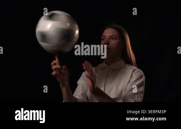 Young woman in a white shirt reaches upward toward a glossy metallic ...
