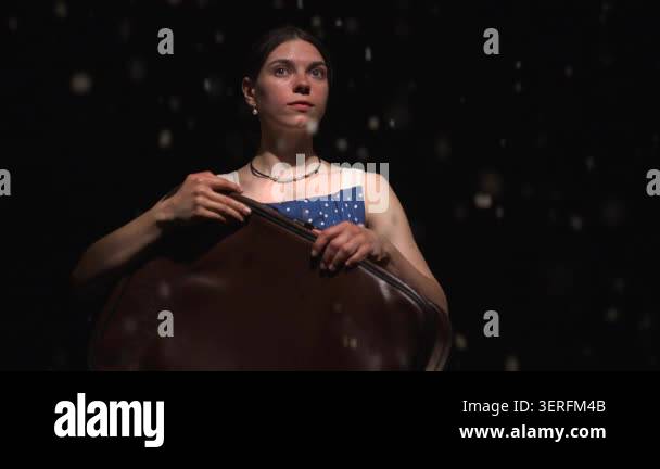 Focused young woman performs with a string instrument in dramatic low ...