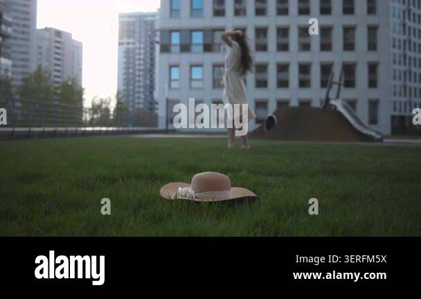 A straw hat rests on green grass in the foreground of a modern ...