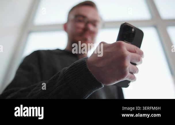 White Man Inspecting Phone Camera Near Window, Low Perspective Closeup ...