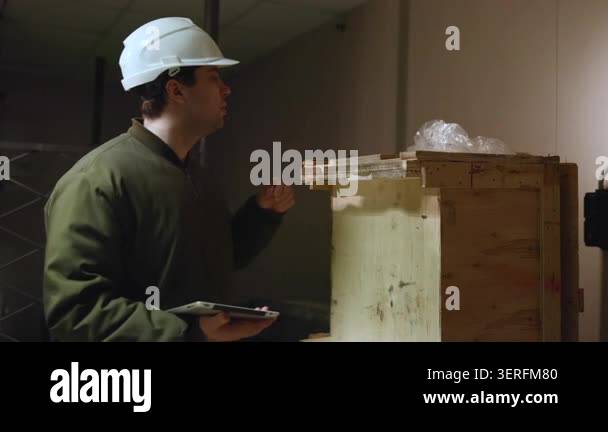 White Inspector Checking Wooden Crate In Dim Storage Room Using Tablet ...