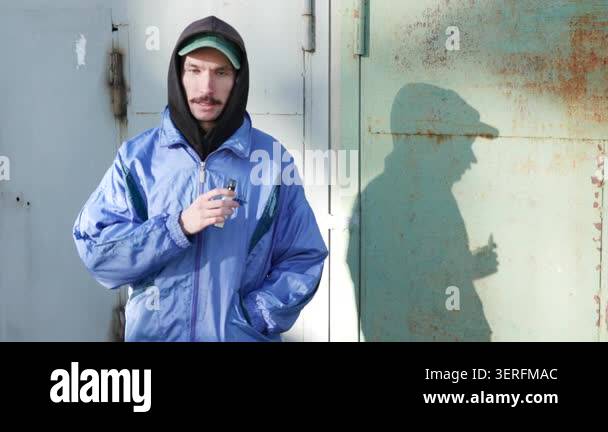 Man In Hooded Jacket Exhaling Smoke Against Rusted Metal Door, Shadow ...
