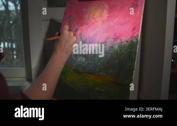 Close-up of an artists hand using a brush to paint a colorful abstract ...