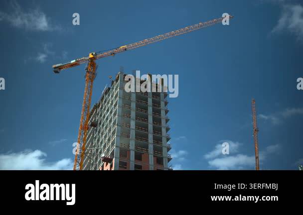 A tall high-rise building is under construction with a large tower ...