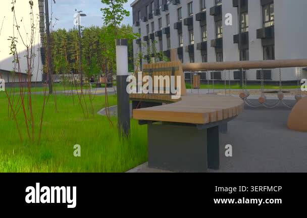 A wooden bench stands in the foreground of a landscaped apartment ...