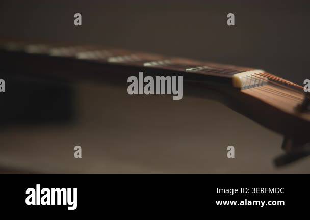 Abstract close-up of guitar strings and body in warm low light, with ...