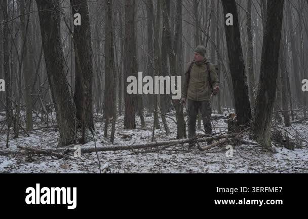 Bushcraft hiker carrying axe through snowy forest during winter ...