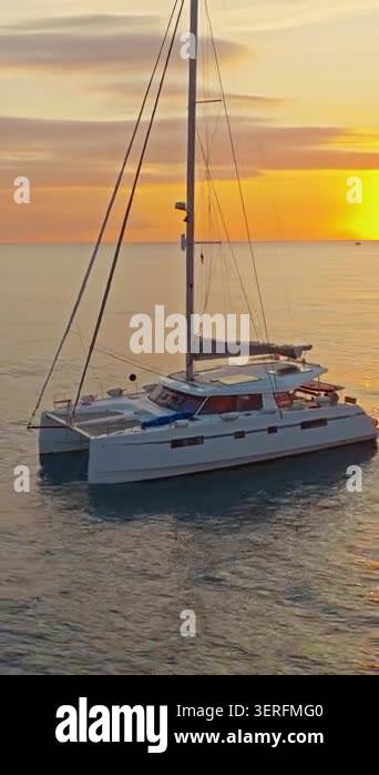 Aerial view of catamaran anchored in the calm sea at amazing sunset ...