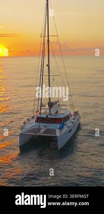Aerial view of catamaran anchored in the calm sea at amazing sunset ...