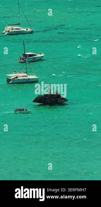 Aerial view of boats and catamarans with tourists and a passing ...