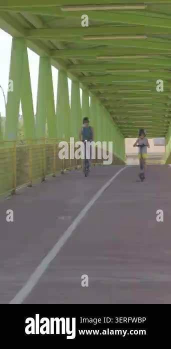 Mother and her child riding electric scooters on a bike path across a ...