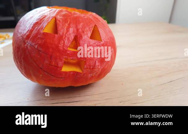 Freshly carved orange pumpkin with a spooky face sitting on a wooden ...