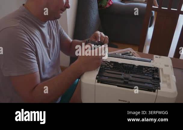 Young man installing new toner cartridge into a multifunction laser ...