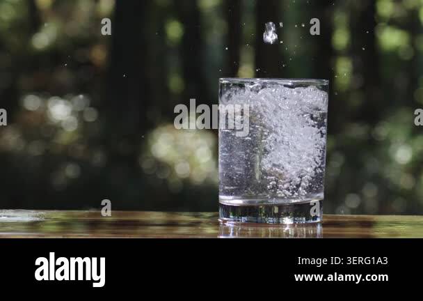 Refreshing water glass outdoors. Pure water bubbles rising in glass ...