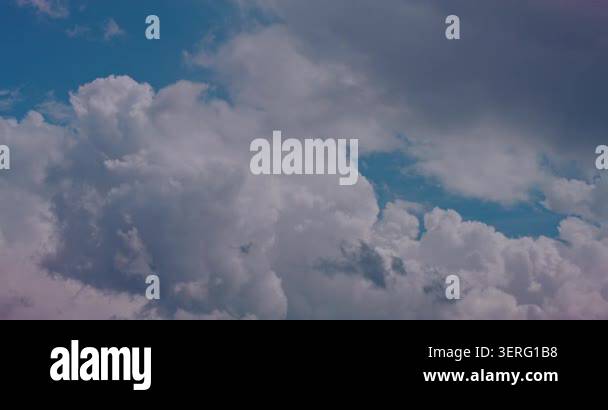 Large white cumulus clouds move across a clear blue sky creating a ...