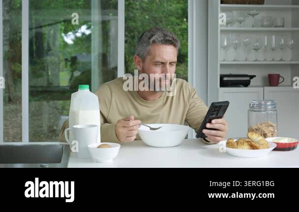 Man having casual phone call during cereal breakfast. Man using mobile ...
