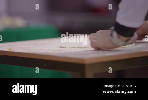 Close up view of hands kneading soft dough on a wooden table with a ...