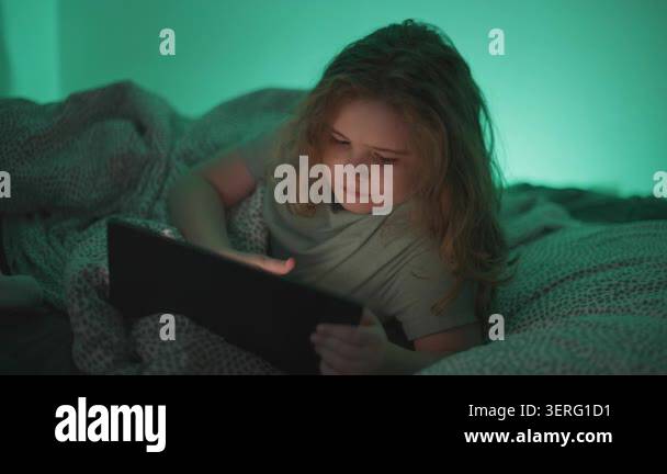 Child watching tablet at home bed. Child using tablet during evening ...
