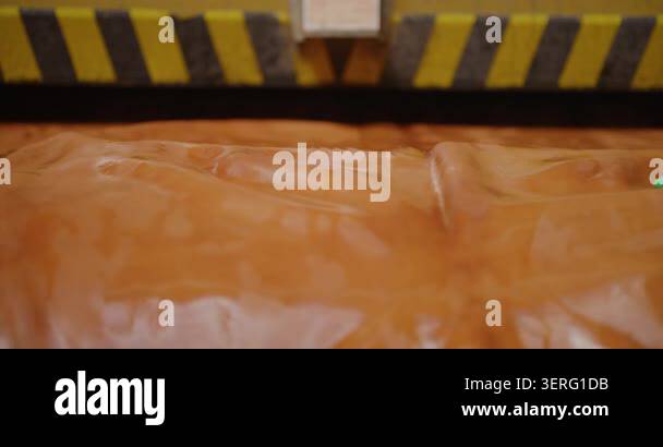 Close-up of a glossy orange protective tarp in the foreground with a ...