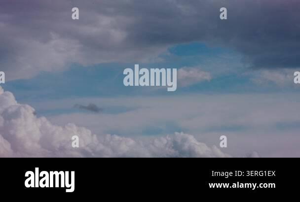 Large white cumulus clouds move across a clear blue sky creating a ...
