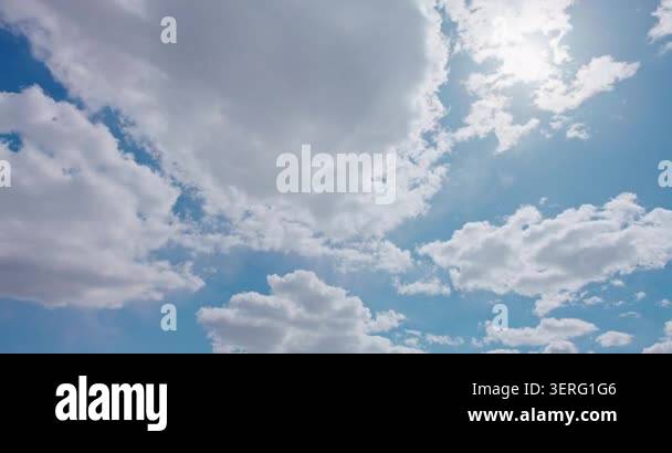 Large white cumulus clouds move across a clear blue sky creating a ...