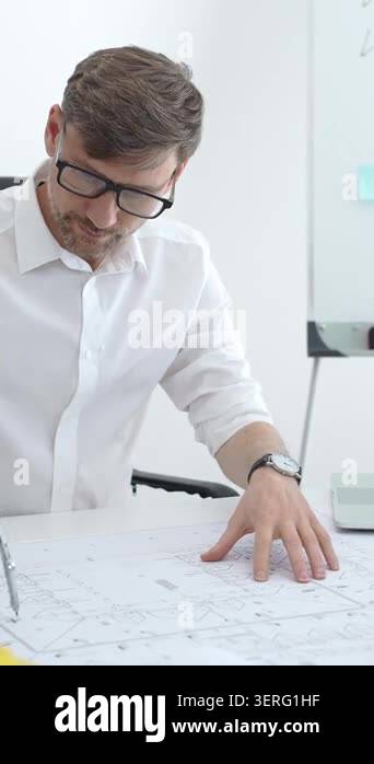 Male architect planning a new construction project, drawing on ...