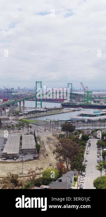 Cars driving across Vincent Thomas Bridge near a massive industrial ...