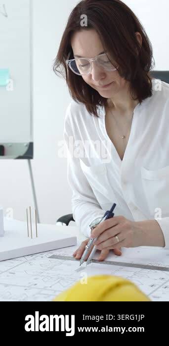 Female architect in office carefully drawing blueprint for new ...