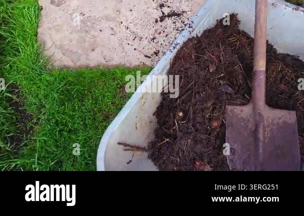 A person is actively engaged in gardening tasks, moving rich soil and ...