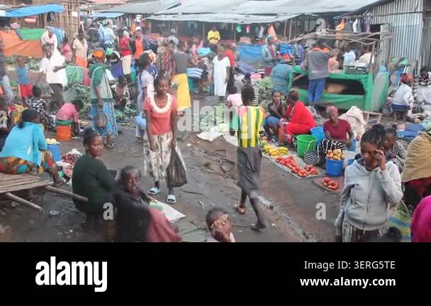 Busy outdoor market scene with many people browsing and selling produce ...