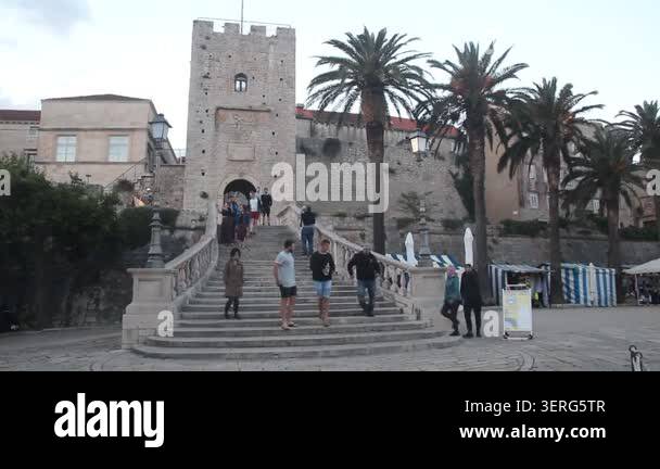 People walking up stone stairs towards ancient fortress gate with palm ...