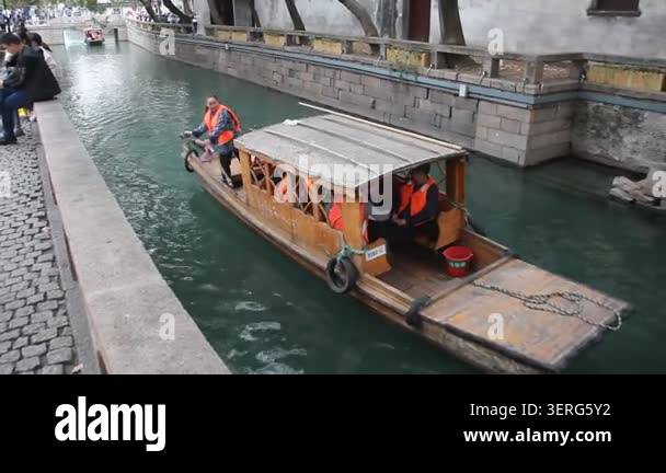 Woman rowing wooden boat with passengers on canal, traditional ...