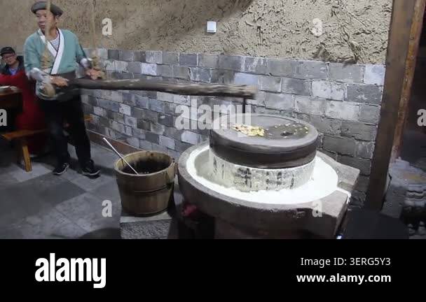 Man operating traditional stone mill grinding grain, traditional food ...