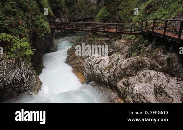 Wooden walkway bridges over a rushing river flowing through a rocky ...