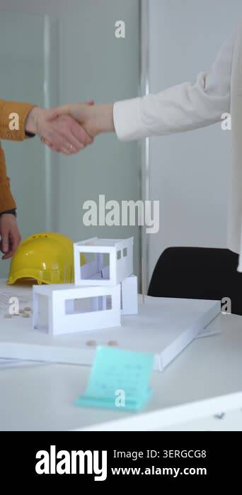 Business partners architect and client shaking hands over a building ...