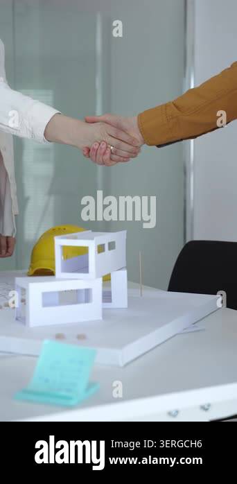 Business partners architect and client shaking hands over a building ...