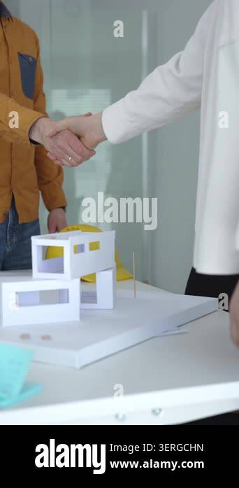 Business partners architect and client shaking hands over a building ...