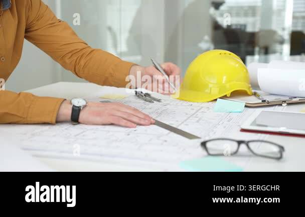 Engineers hands sketching and annotating architectural blueprints on a ...