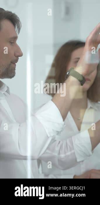 Business colleagues are actively collaborating on a glass board ...