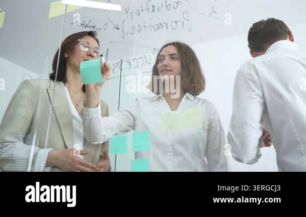 Business professionals collaborating on a transparent glass board ...